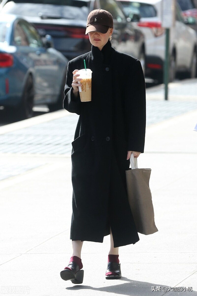Emma Stone is wearing a black suit coat + wine red socks + baseball cap ...