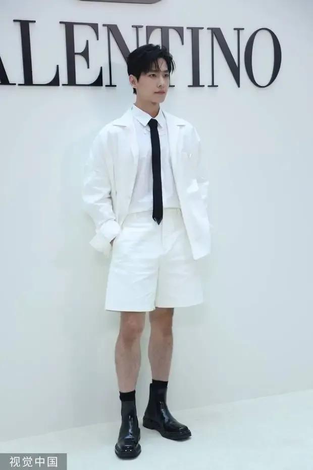 Yang Yang wore a white suit to attend the event, with his hands in his ...
