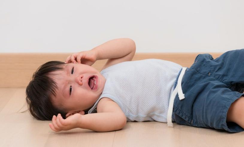 The child is crying and rolling in the shopping mall, the mother has a ...