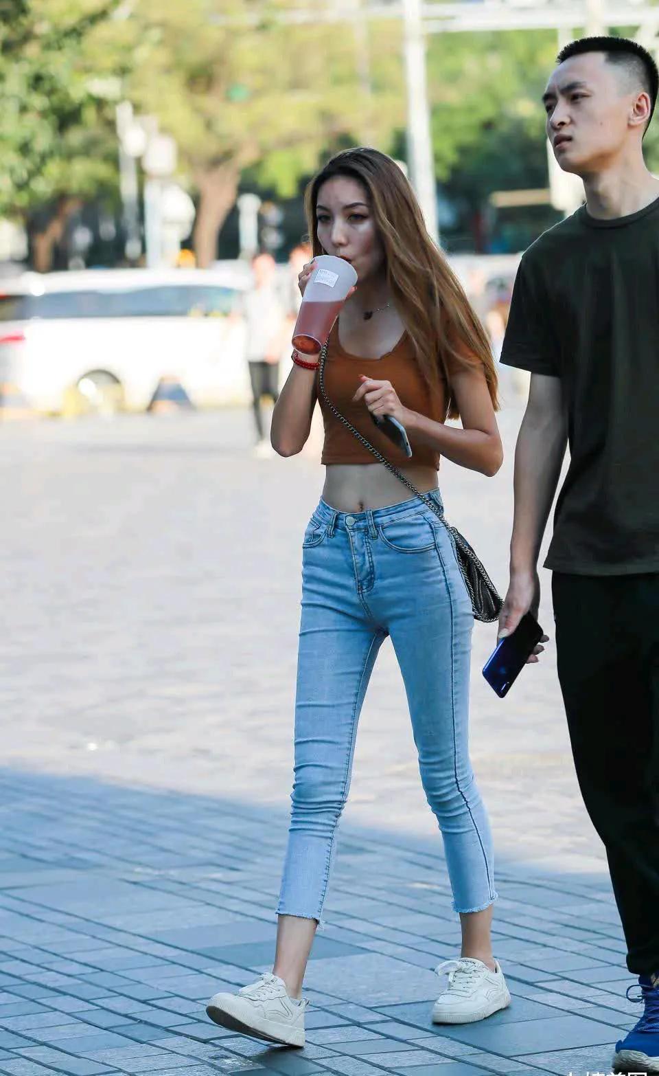 The beautiful woman wears skinny jeans with her navel exposed, she is ...