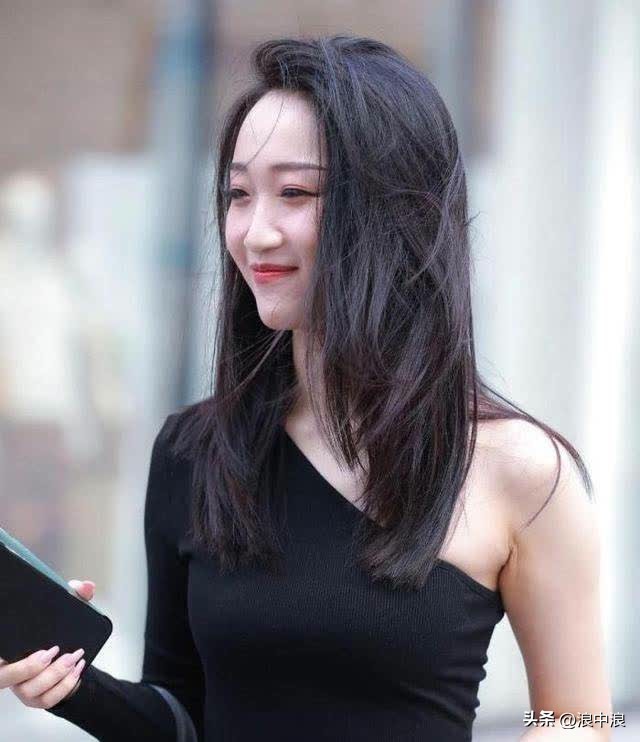 The black one-piece dress outlines the girl's beautiful curves, showing ...