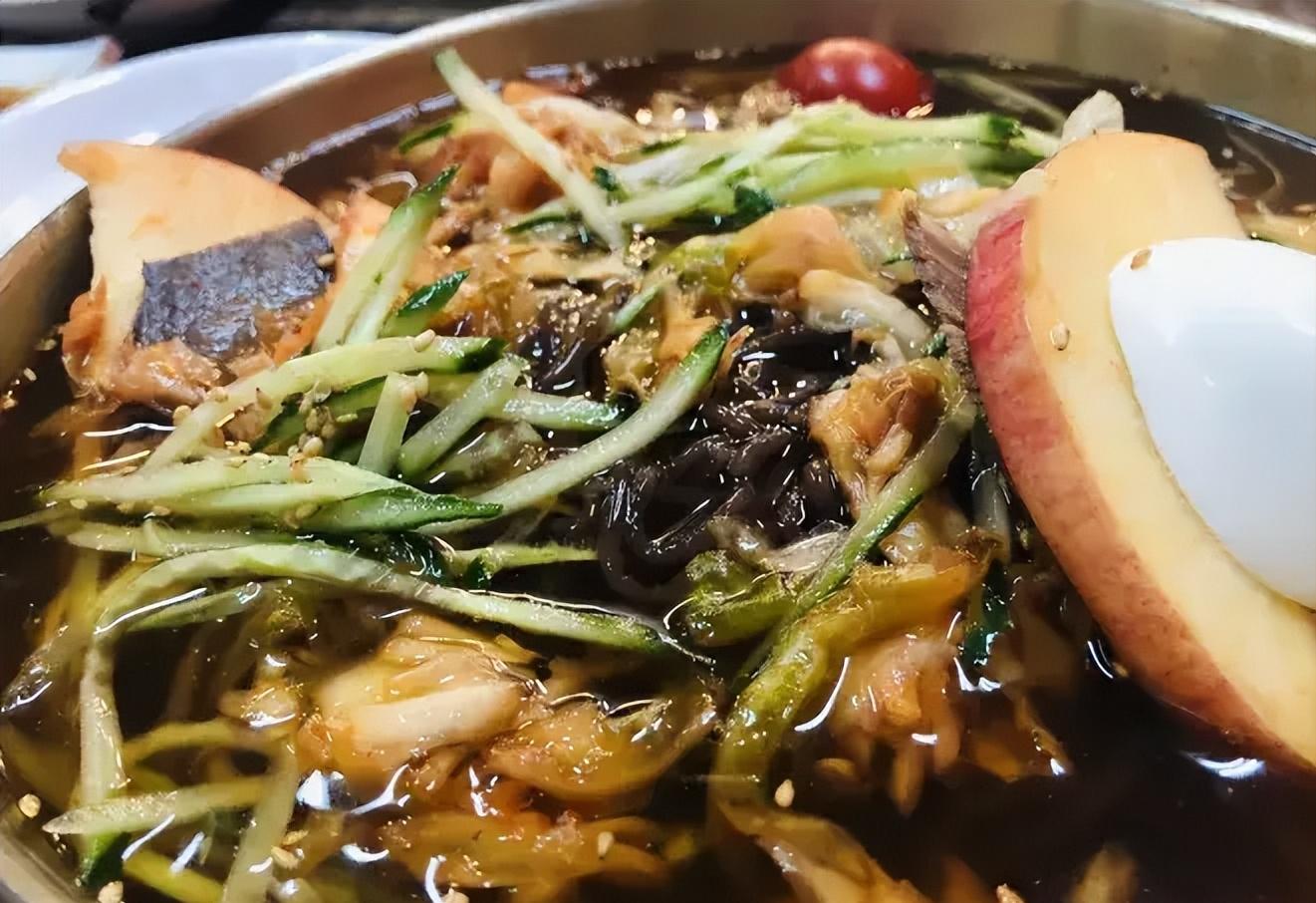 A bowl of Yanji cold noodles, a plate of spicy beef, and a draft of ...