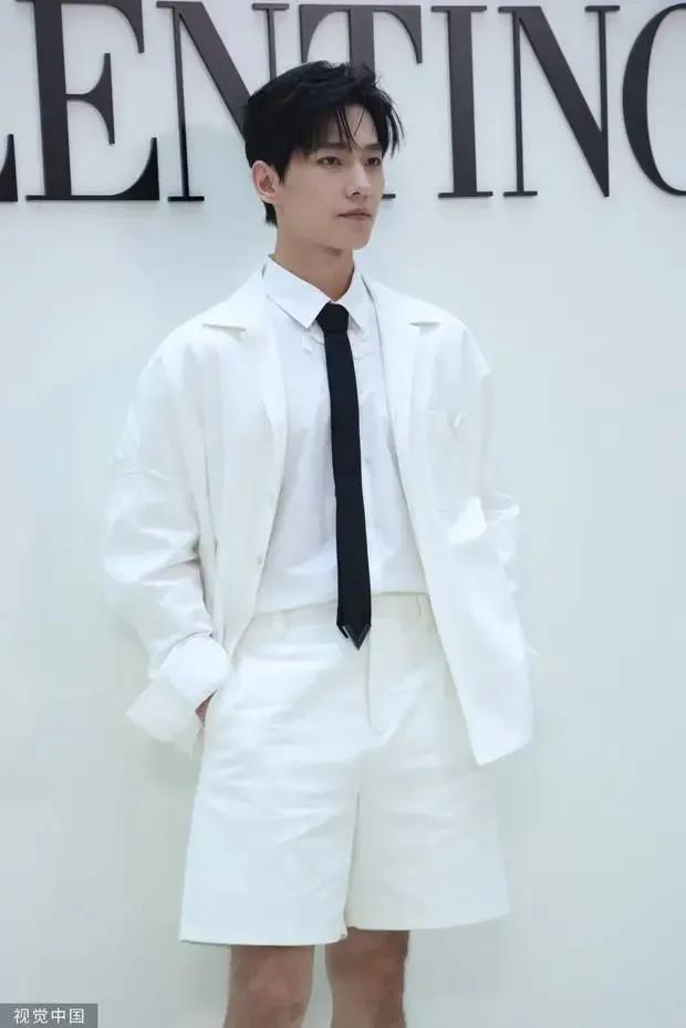 Yang Yang wore a white suit to attend the event, with his hands in his ...