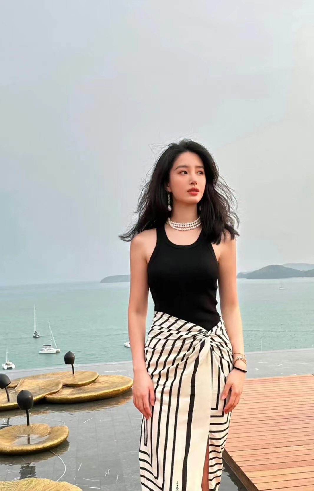 Yang Caiyu is on vacation at the seaside, wearing a black vest with a ...