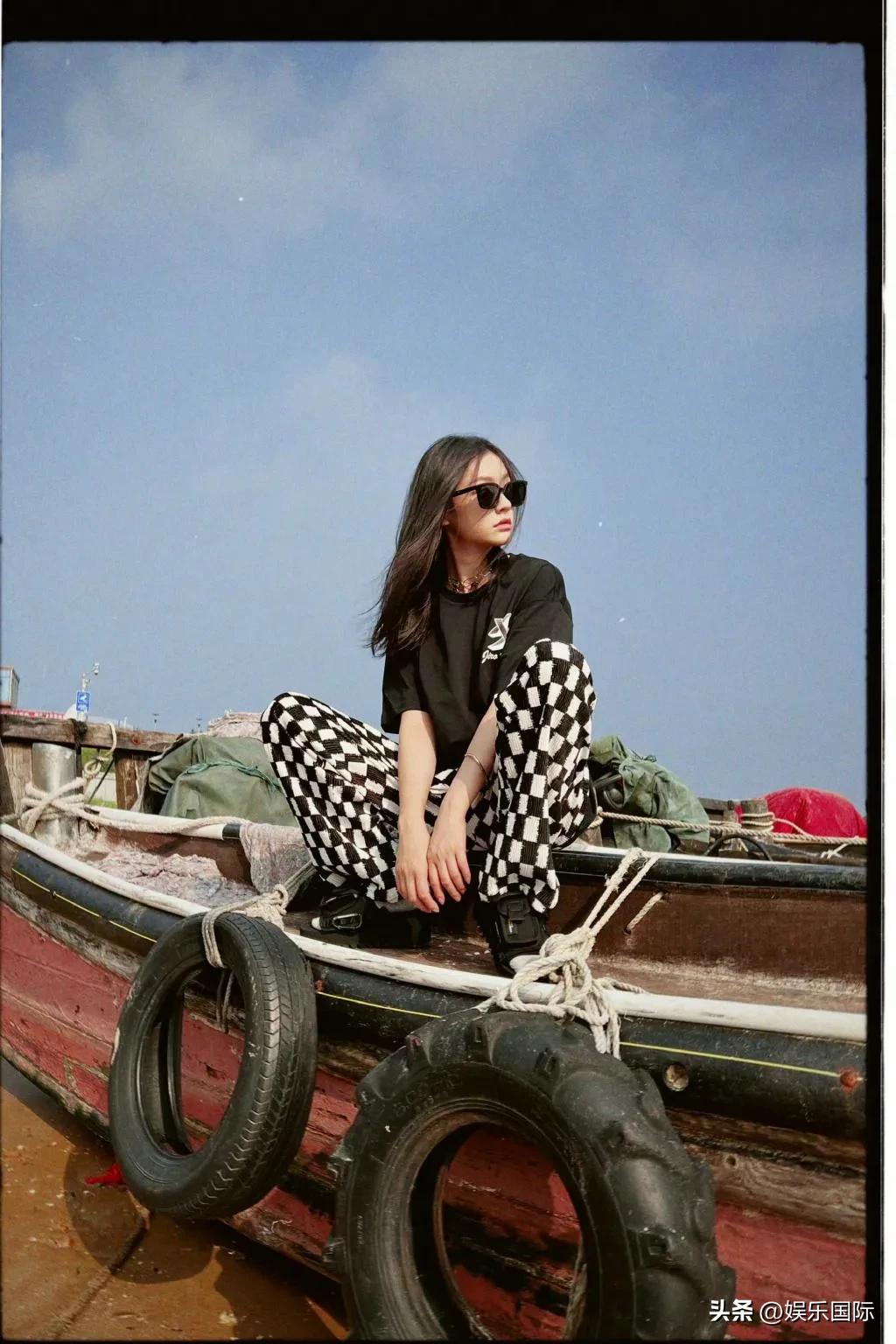 Lin Yun basks in the beach and wears sunglasses while squatting on a ...
