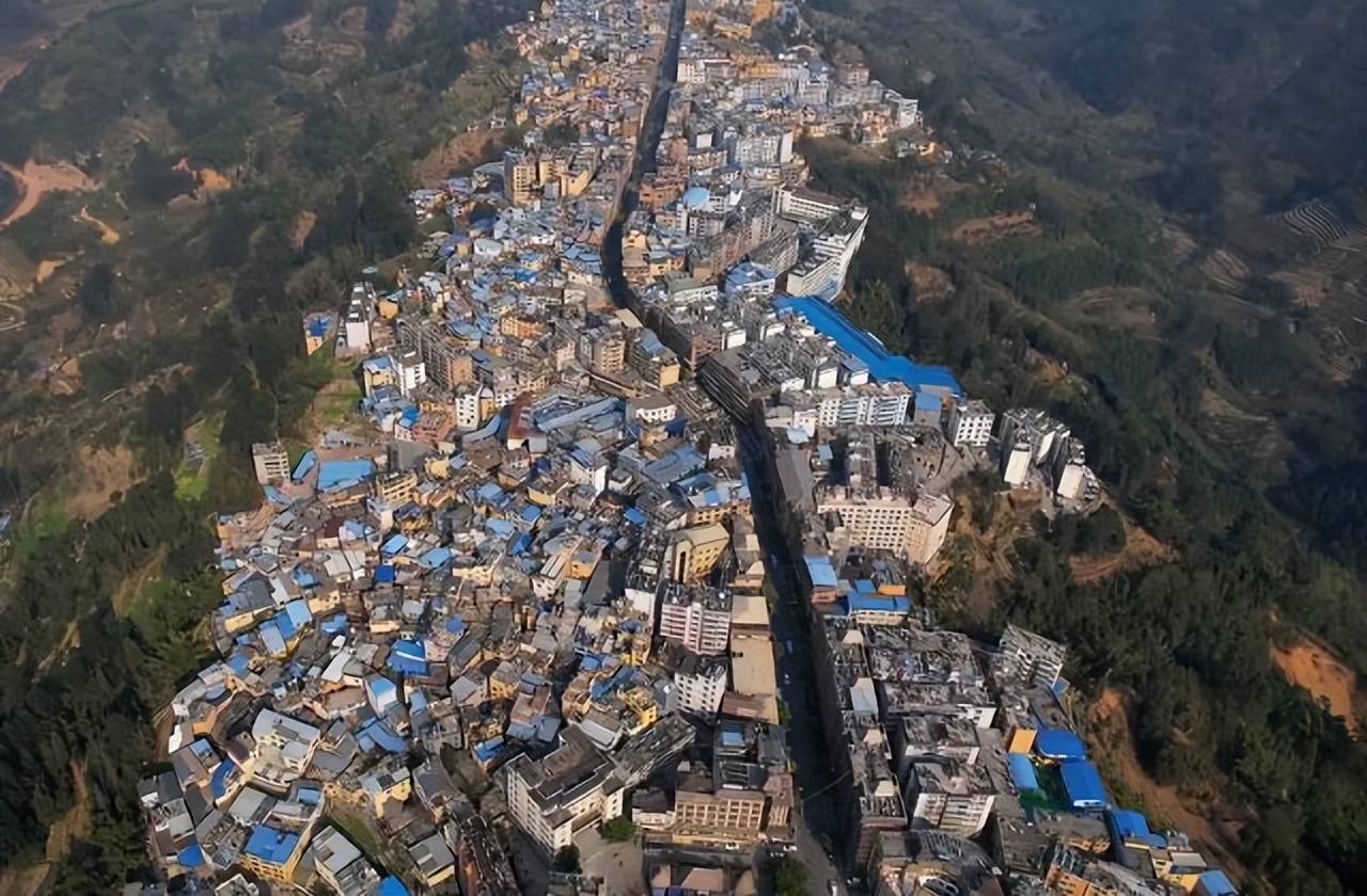 A small town built on the top of a mountain in Yunnan, with cliffs on ...