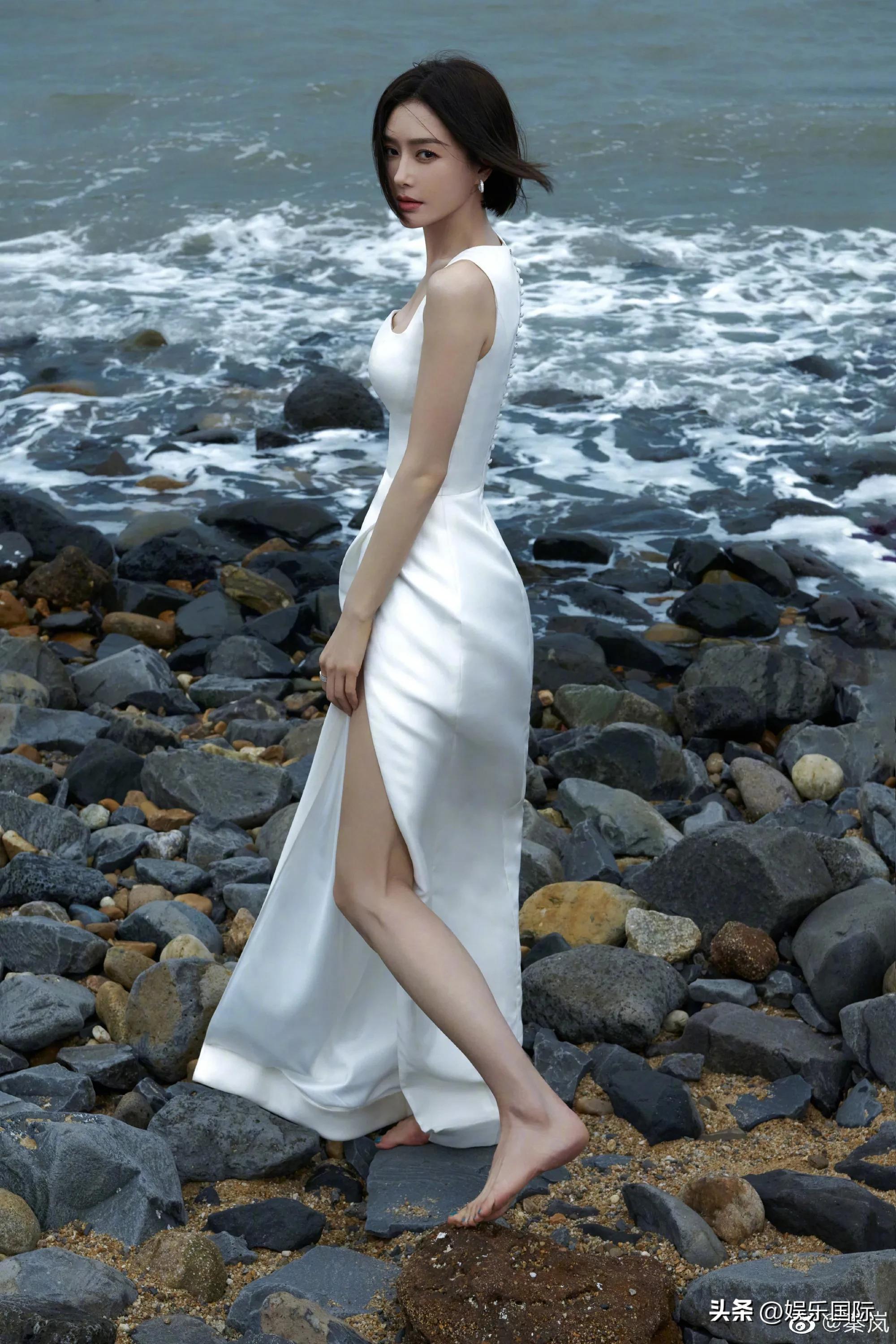 Qin Lan stood barefoot on the beach and took pictures wearing a white ...